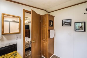 Quarto com cama, guarda-roupa de madeira, espelho e quadro pendurado na parede.