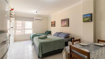 Quarto com cama, escrivaninha e cadeira. Há uma janela e uma porta.