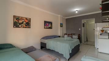 Quarto com duas camas, uma mesinha e um frigorífico.