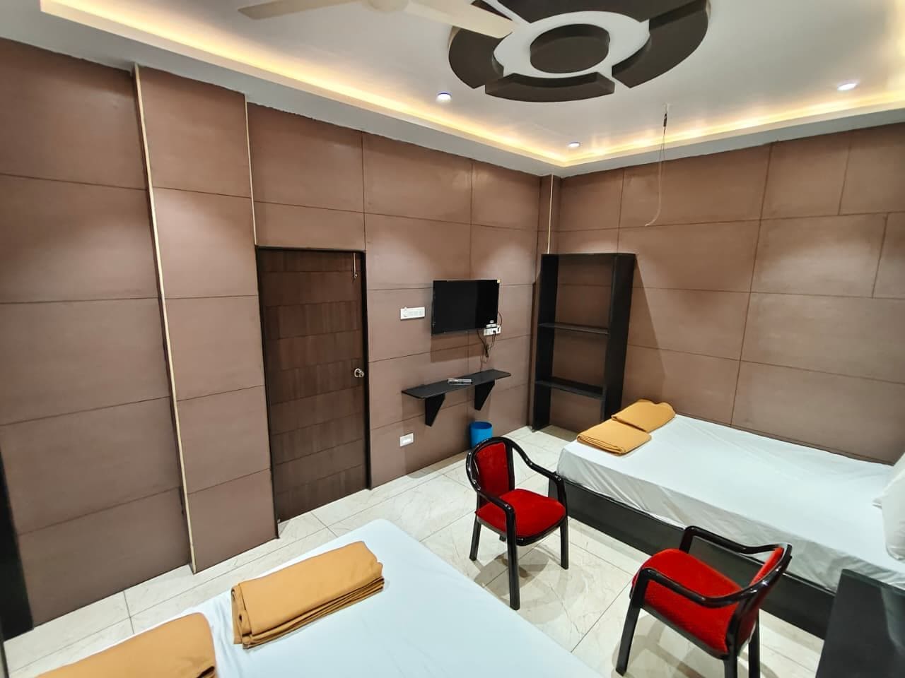 Quarto de hotel com duas camas, televisão, escrivaninha e cadeira.