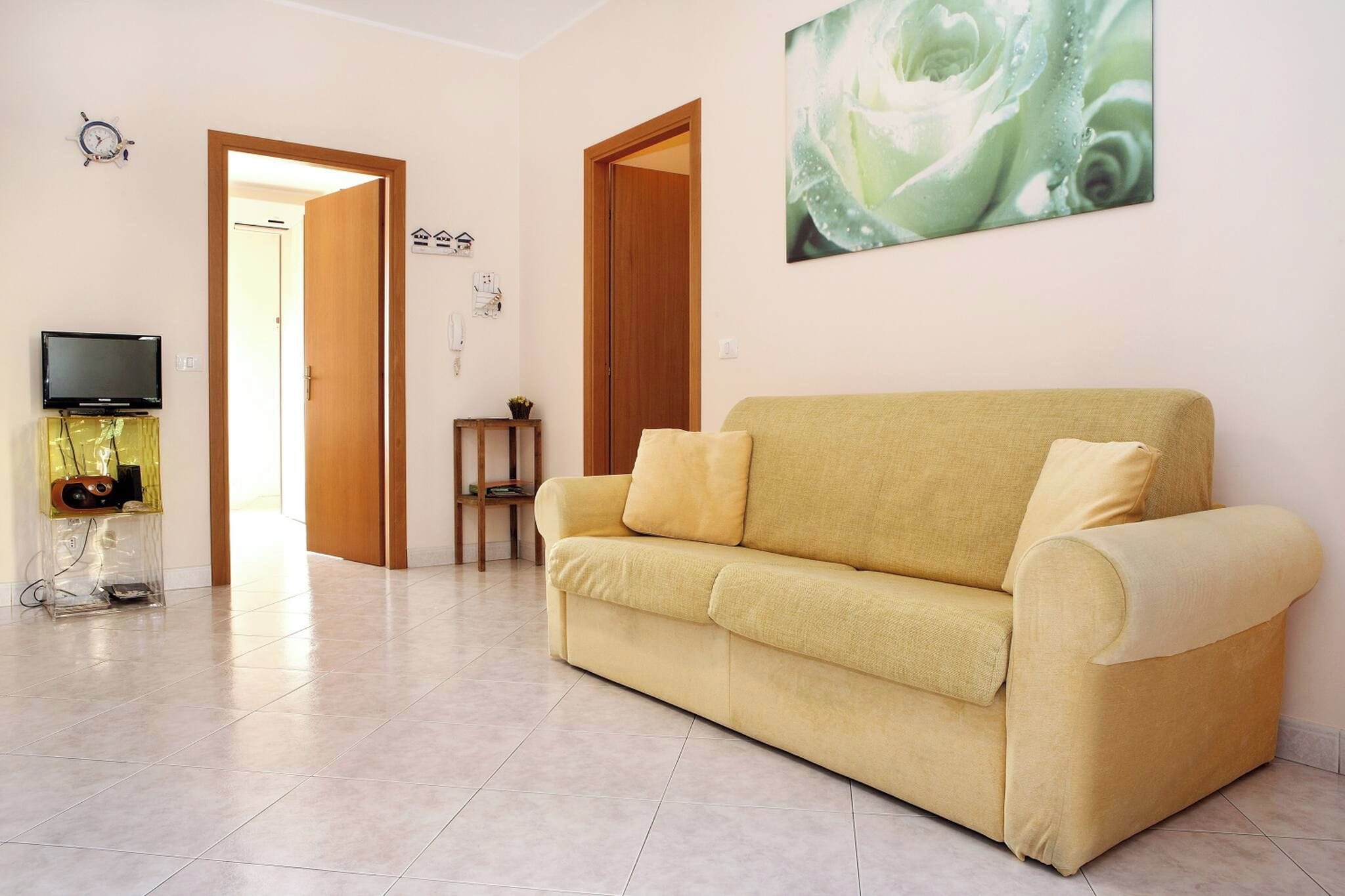 Uma sala de estar com sofá, televisão e um quadro na parede.