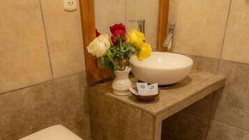 Casa de banho com sanita, lavatório e um vaso com flores.