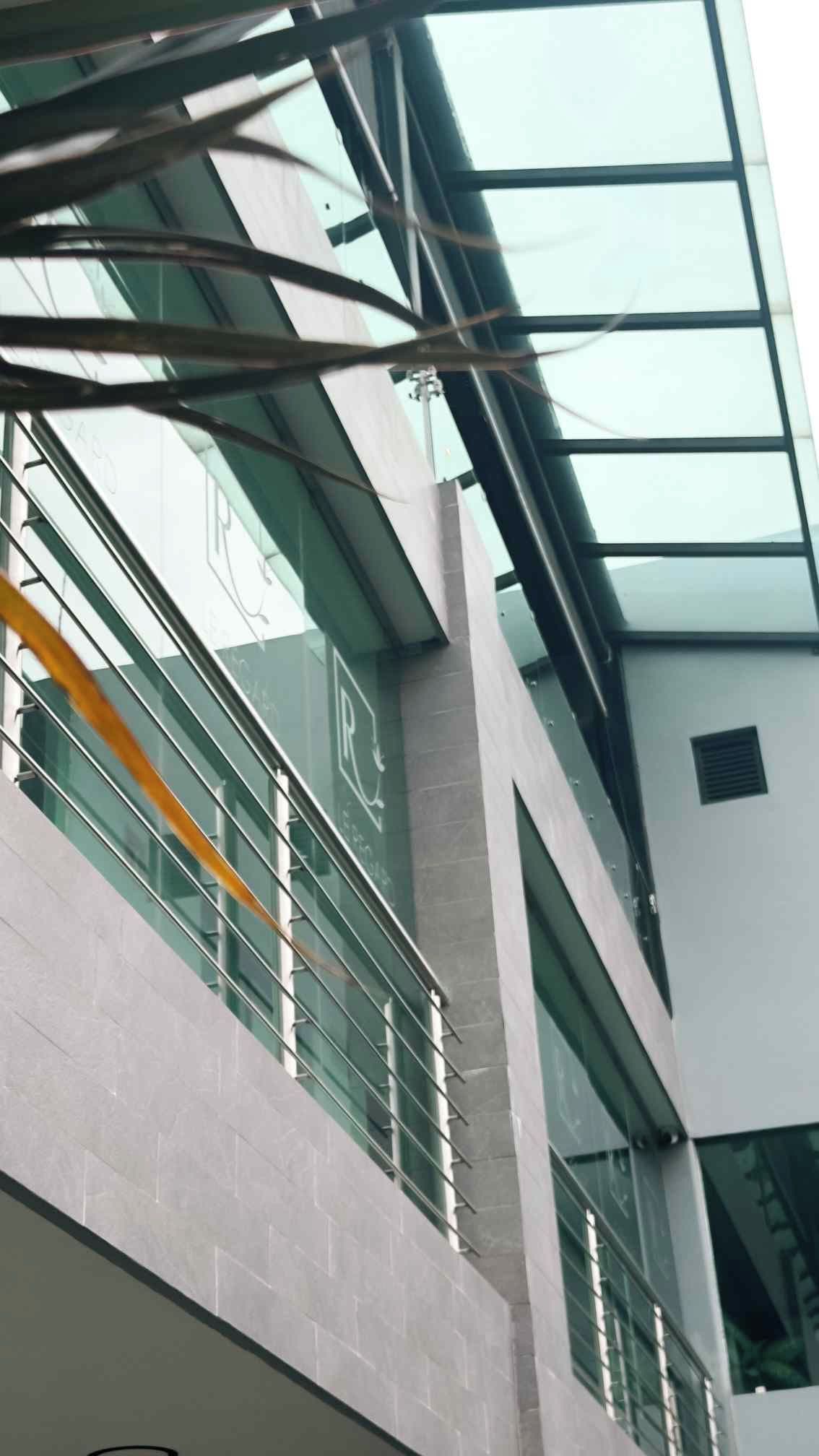 Um edifício moderno com fachada de vidro e guarda-corpos de metal.