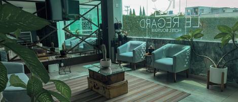 Um hall de hotel moderno com assentos, uma mesa de centro de vidro e vista para a cidade.