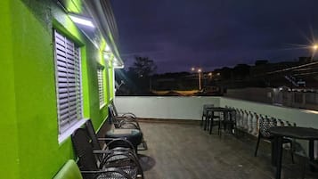 Área de estar ao ar livre com assentos e vista para a cidade ao anoitecer.