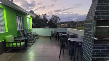 Terraço no telhado com área de estar ao ar livre, forno de tijolos e parede verde.