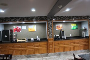 Uma área de recepção de hotel com balcão, frigorífico e máquina de café.