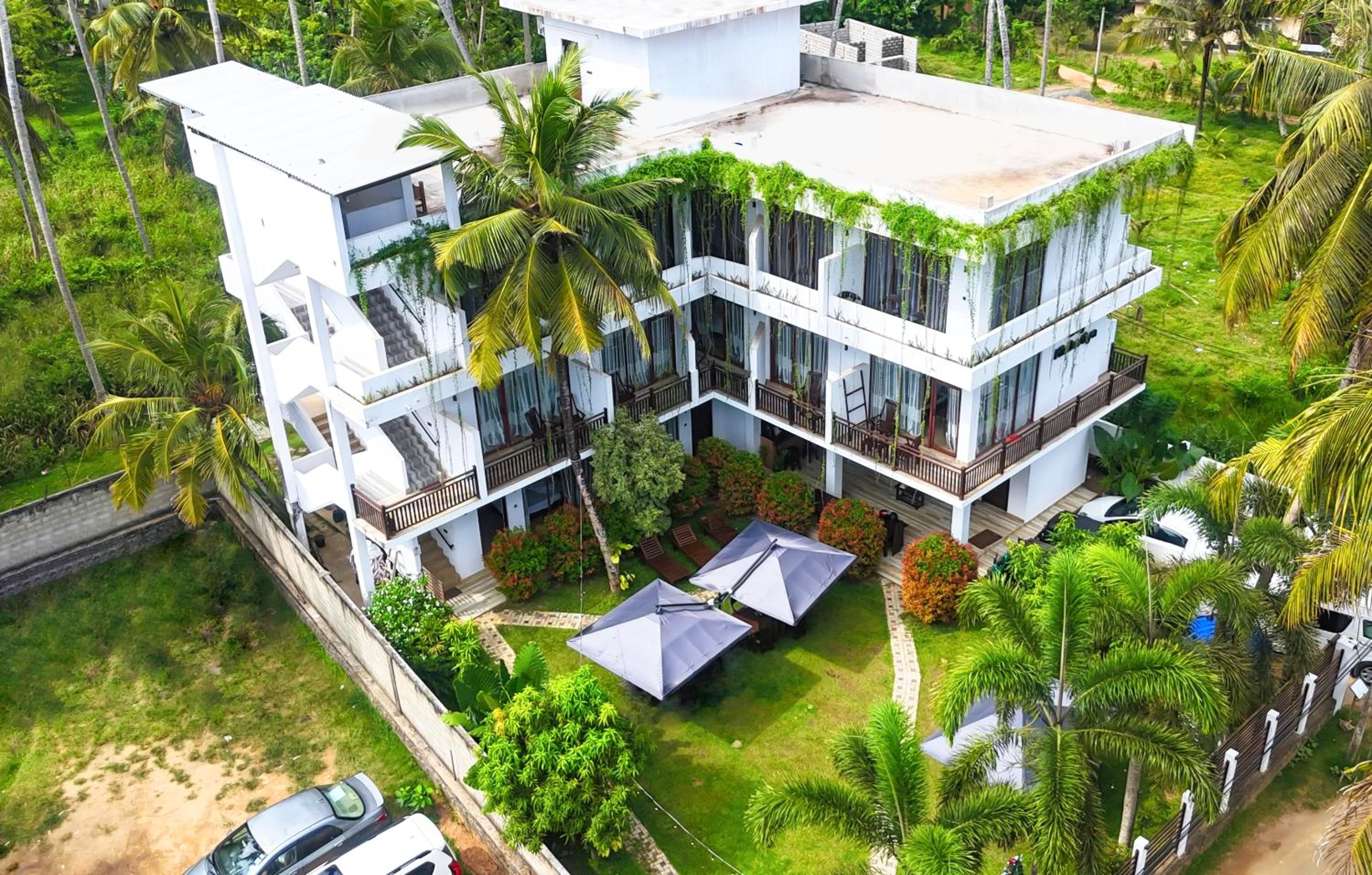 Edifício com várias andares, varandas e um jardim.