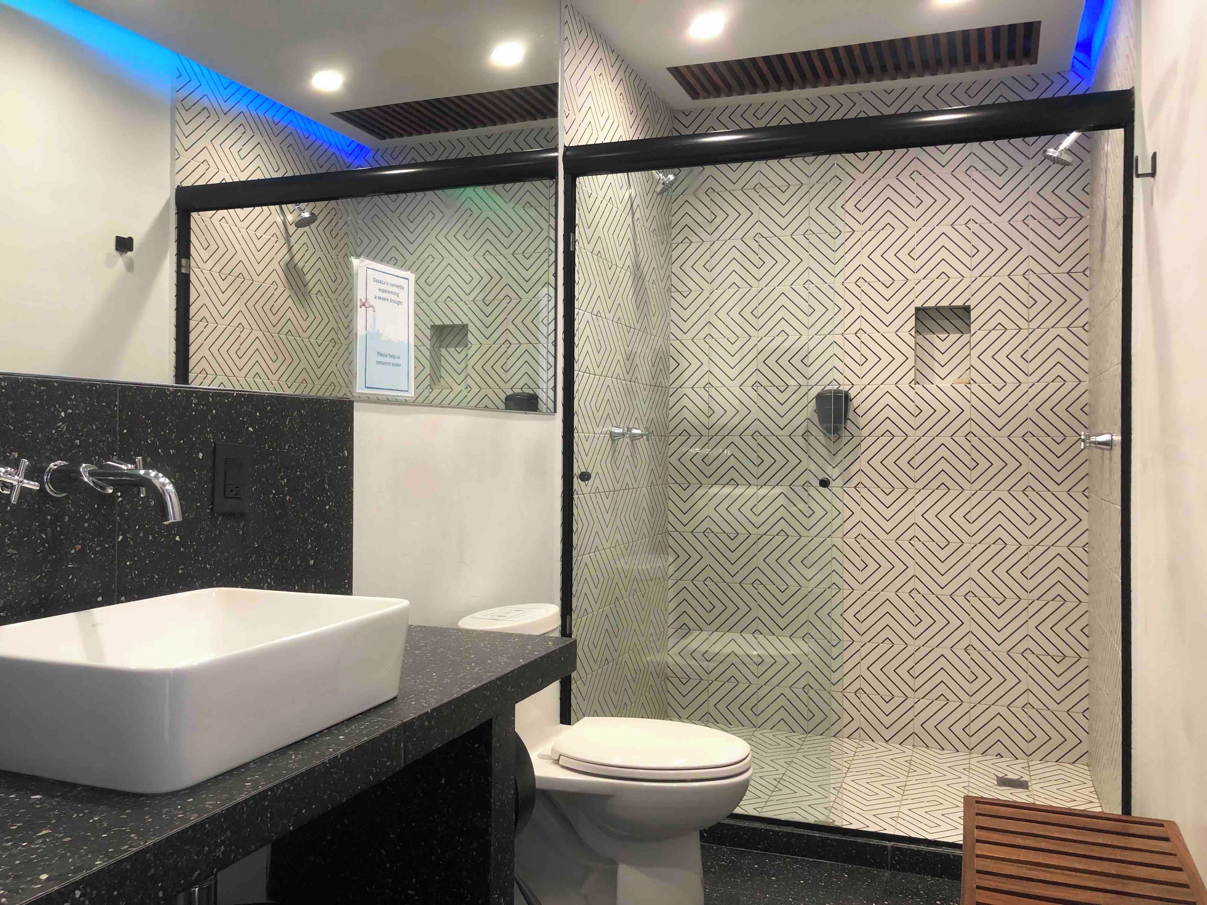 Casa de banho moderna com bancada preta, lavatório branco e sanita.
