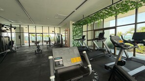 Academia com esteiras, aparelhos de musculação e uma parede coberta de plantas.