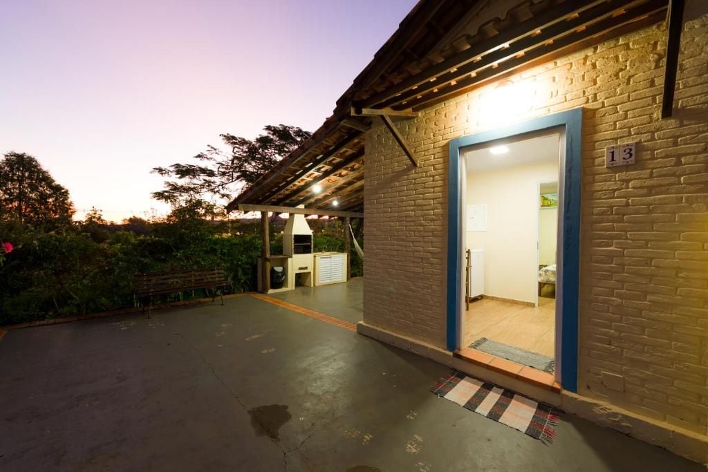 Um edifício com fachada de tijolos, uma porta com o número 13 e uma área externa coberta com um banco.