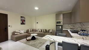 Uma sala de estar moderna com um sofá seccional, uma mesa de centro e uma área de jantar com mesa de bancada em mármore.