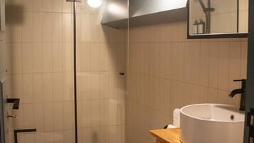 Uma casa de banho com sanita, chuveiro e lavatório.
