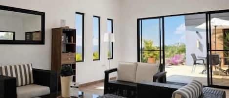 Uma sala de estar moderna com sofá, mesa de centro e uma janela grande.