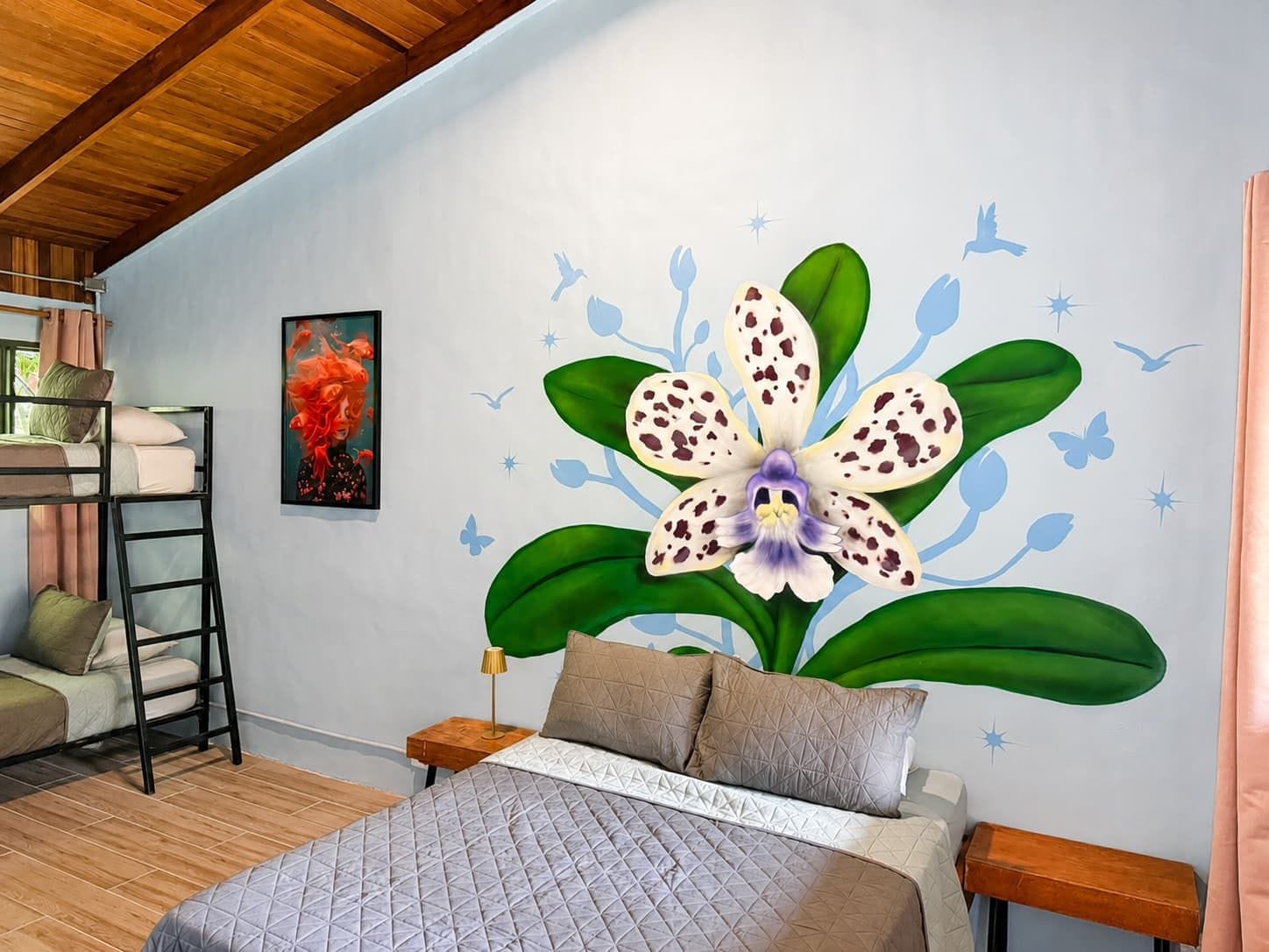 Quarto com beliche, um grande mural de orquídeas e uma pintura na parede.