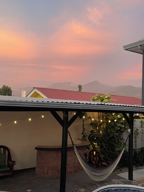 Área externa coberta com rede, luzes de festa e vista para montanhas ao longe.