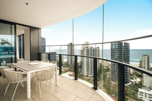 Varanda com mesa e cadeiras, vista para a cidade e o oceano.
