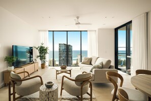 Uma sala de estar moderna com televisão, assentos, área de jantar e vista para o horizonte urbano através de grandes janelas.