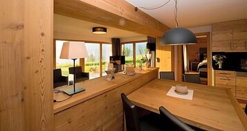 Interior em madeira com área de jantar, cozinha e uma janela grande.