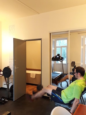 Uma academia em casa com equipamentos de exercício, um espelho e uma porta que dá para outro cômodo.