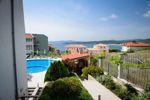Área residencial com piscina, vista para o mar e um morro.
