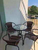 Varanda com mesa de vidro redonda e quatro cadeiras de vime.