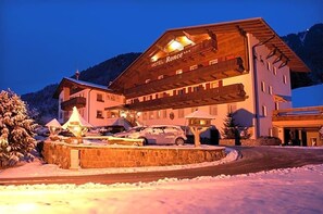 Um hotel com fachada de madeira, várias varandas e paisagem coberta de neve.