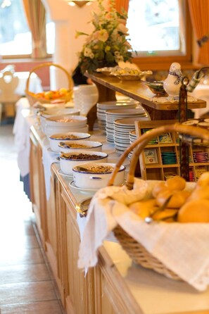 Disposição de buffet com diversos alimentos e um pássaro decorativo em um pedestal.
