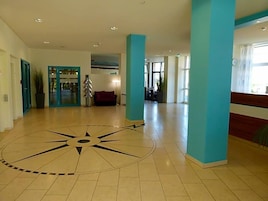Um hall amplo com um grande design no chão, um balcão de recepção e uma área de estar.