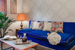 Uma sala de estar acolhedora com um sofá azul, uma mesa com uma bandeja de bebidas e uma luminária.