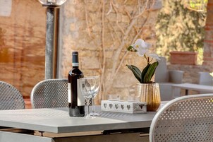 Mesa posta com uma garrafa, copos e um vaso com uma orquídea.