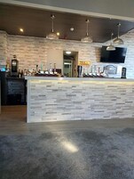 Uma área de bar com parede de pedra, luminárias pendentes e uma TV de tela plana fixada acima do balcão.