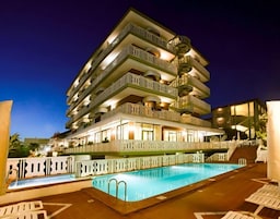 Um hotel com vários andares, piscina e área de estar ao ar livre.