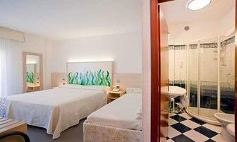 Quarto de hotel com duas camas, banheiro com chuveiro e piso xadrez.