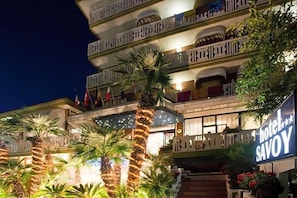 Um hotel com vários andares, varandas e uma placa com a inscrição 'hotel SAVOY'.