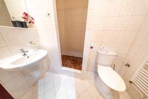 Casa de banho com lavatório branco, sanita e zona de duche.