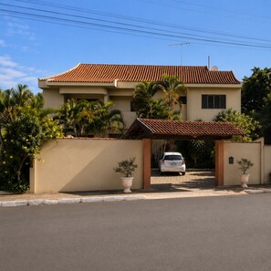 Uma casa de dois andares com telhado de telhas, uma entrada coberta e um carro branco estacionado na garagem.