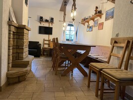 Uma área de refeições acolhedora, com uma mesa e cadeiras de madeira, televisão na parede e lareira.