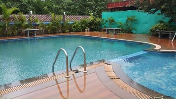Piscina com deck de madeira e corrimãos de metal.