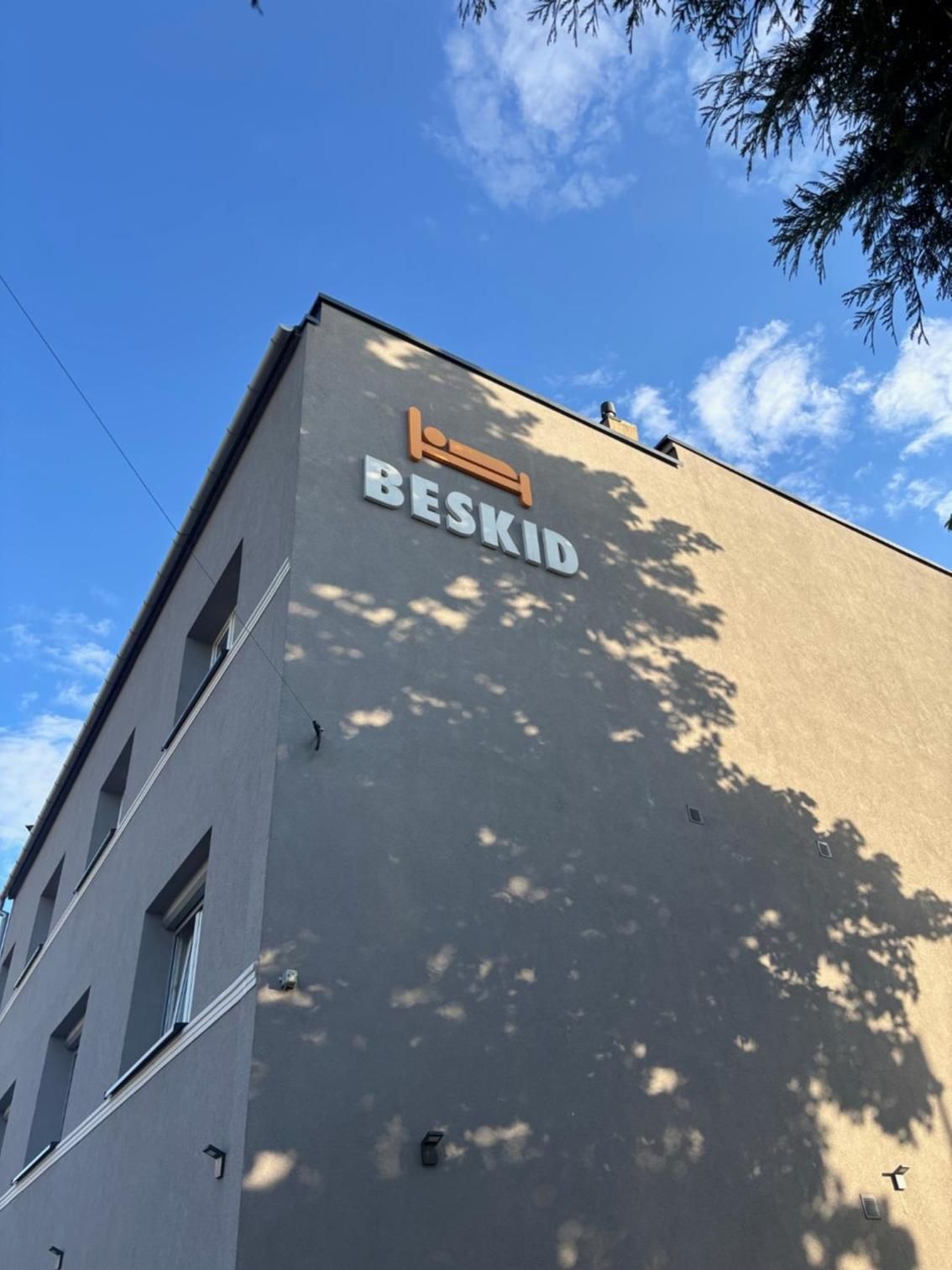 Um edifício com uma placa que diz 'BESKID' e um ícone de cama, indicando um hotel ou acomodação.