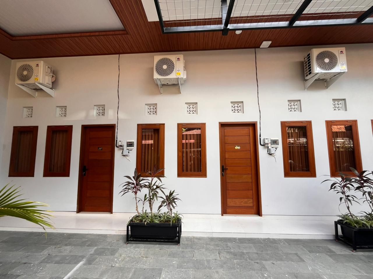 Fachada de prédio com várias portas e janelas, aparelhos de ar condicionado e plantas em vasos.