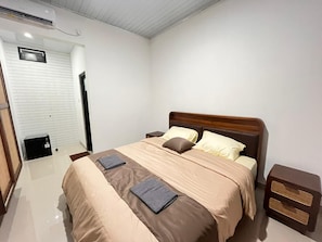 Quarto de hotel com cama, mesas de cabeceira e guarda-roupa.