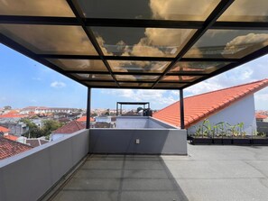Terraço no telhado com teto de vidro, vista panorâmica da cidade e fileira de plantas.