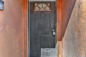 Uma porta de madeira escura com um painel de vidro e uma fechadura de metal.