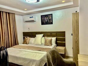 Quarto de hotel com cama, mesa de cabeceira, cadeira e ar condicionado.