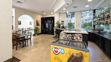 Um restaurante com área de bar, exposição de sorvete de sundae e vista para o exterior através de grandes janelas.