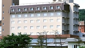 Um hotel com vários andares, fachada plana, diversas janelas e entrada visível.