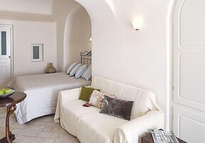 Quarto com cama, sofá, uma mesinha com maçãs e revista.