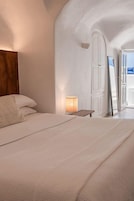 Quarto com cama, luminária de cabeceira e porta que dá para uma varanda.