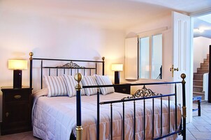 Quarto com cama, mesas de cabeceira, luminárias, espelho e escada.